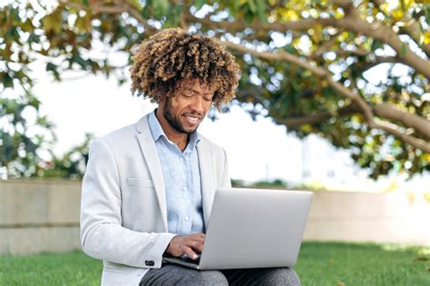 긍정적 인 똑똑한 성공적인 브라질 또는 라틴계 곱슬 남자 회사 Ceo 프로그래머 콘텐츠 관리자 노트북으로 야외에 앉아 프로젝트에서 온라인으로 작업 인터넷 검색 행복하게 웃고