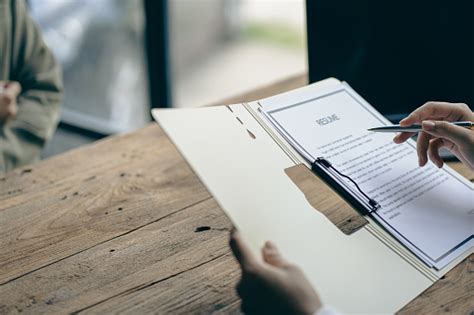 친절한 Hr 관리자는 면접을 주도하고 사무실 책상에서 후보자 중 한 명과 이력서를 읽습니다 2명에 대한 스톡 사진 및 기타