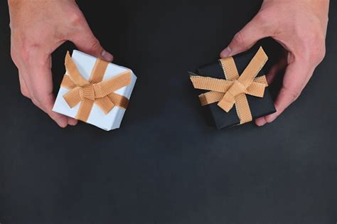 검은 색 배경에 금 리본과 검은 색과 흰색 선물 상자를 들고 손 복사 공간이 있는 플랫 레이 컴포지션 2명에 대한 스톡 사진 및 기타 이미지 Istock