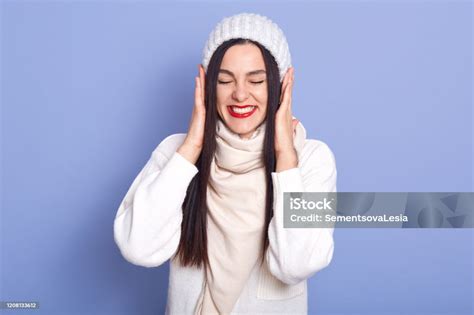 스튜디오에서 파란색 배경 위에 고립 된 감정적 인 매력적인 젊은 갈색 머리의 이미지 눈을 감고 이빨이 있는 미소를 지으며