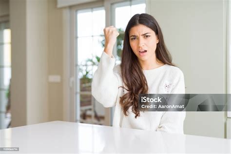 흰색 테이블에 집에서 젊은 아름 다운 여자 화가 분노와 소리를 지르는 동안 좌절 주먹과 분노를 제기 분노와 공격적인 개념 가정 생활에 대한 스톡 사진 및 기타 이미지