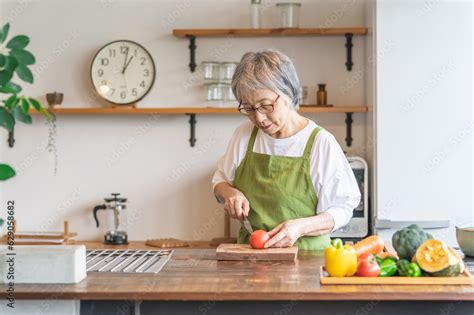 家のキッチンで料理を作るアジア人のシニア・高齢者女性 Stock 写真 Adobe Stock