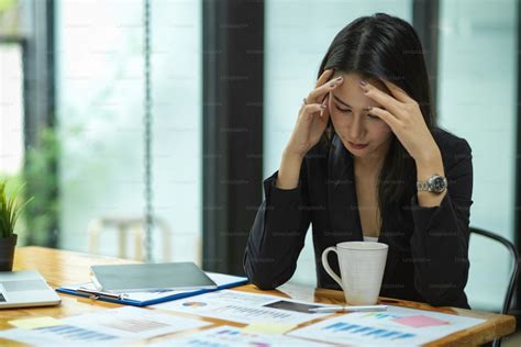 매력적인 사업가는 재무 보고서 태블릿 노트북 사무실의 나무 책상에 커피 컵으로 직장에서 스트레스를 받고 있습니다 사진 Unsplash의 태국 이미지