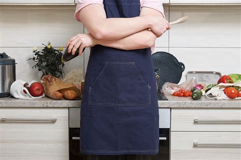 부엌에 앞치마를 입고 있는 백인 남성이 부엌에 서서 채소와 나무 숟가락을 들고 요리하기 위해 준비 부엌에 대한 스톡 사진 및