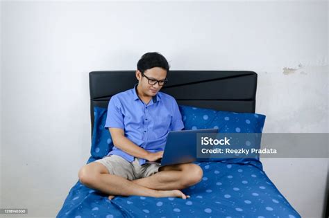 젊은 아시아 남자는 미소와 집에서 일할 때 즐길 수 있습니다 침대에 앉아 노트북 컴퓨터로 일하는 남자 홈 컨셉에서 작업 20