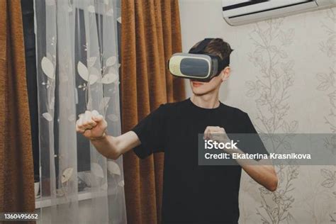 Vr 헬멧을 쓰고 있는 청년이 집 내부의 가상 현실에서 물체와 상호 작용합니다 20 24세에 대한 스톡 사진 및 기타 이미지