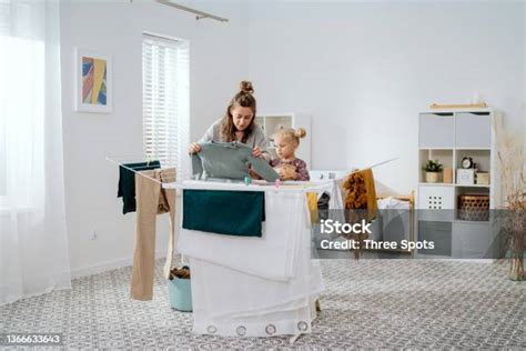 바쁜 엄마는 화장실에서 딸과 함께 시간을 보내고 소녀에게 건조기 어린이 손 여성 의류 클립에 세탁을 걸수있는 방법을 가르치고 집안일을 돕습니다 가족에 대한 스톡 사진 및