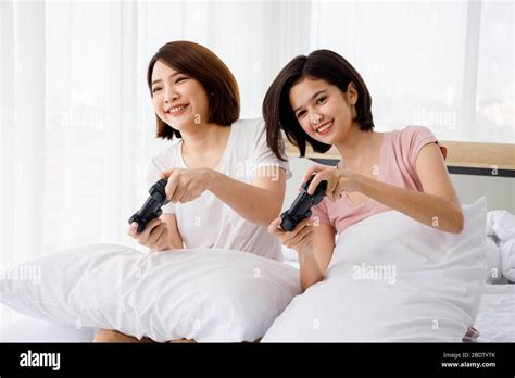 Two Asian Girl Hold Game Controller And Enjoy Video Game Together On