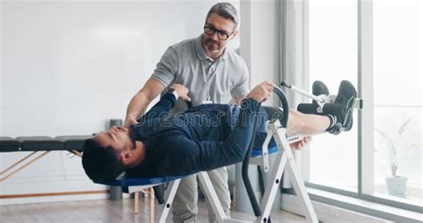 Physiotherapy Consulting And Inversion Table With Man In Clinic For