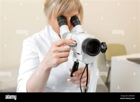 Female Blond Doctor Gynecologist Looks Through A Colposcope