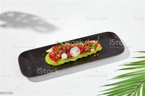 현대 음식 검은 접시에 슬라이스 아보카도에 참치 타르타르 아보카도 스타터와 참치와 무 아시아 스타일 현대 아시아 요리 흰색