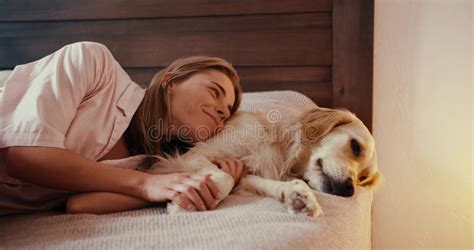 A Blonde Girl In A White Nightgown Lies With Her Light Colored Dog On
