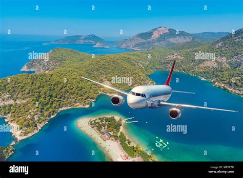 Airplane Is Flying Over Amazing Mountains With Forest And Sea At