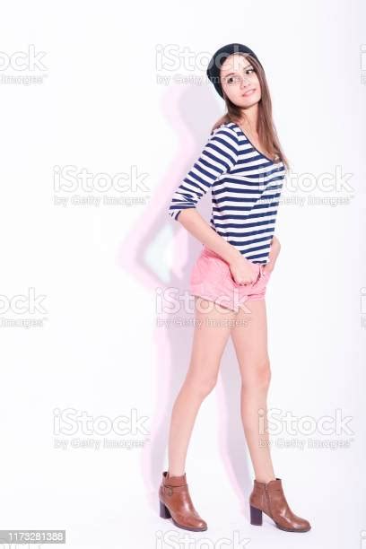 패션과 라이프 스타일 컨셉 모자와 줄무늬 셔츠에 웃는 갈색 머리 소녀의 전체 길이 초상화 흰색에 대한 하이힐에 포즈 수직 이미지 컴포지션 20 24세에 대한 스톡 사진 및