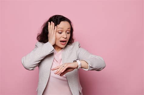 그녀의 손목 시계에 시간을 확인하는 놀란 사업가 비즈니스 회의에 늦고 분홍색 배경에 고립 라틴 아메리카 히스패닉 민족에 대한