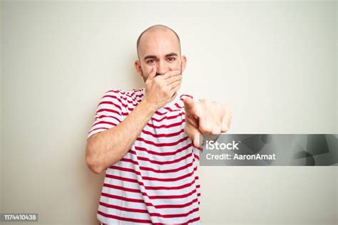 젊은 대머리 남자 와 수염 착용 캐주얼 스트라이프 빨간 티셔츠 위에 흰색 고립 된 배경 웃음 손가락을 가리키는 카메라에 손으로 입 수치 표정 T 셔츠에 대한 스톡 사진 및