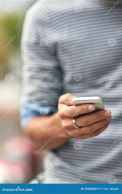 Staying On Schedule Closeup Shot Of A Young Man Texting On A Cellphone