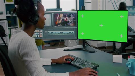 African Woman Videographer With Headset Processing Film Montage Working At Greenscreen Chroma