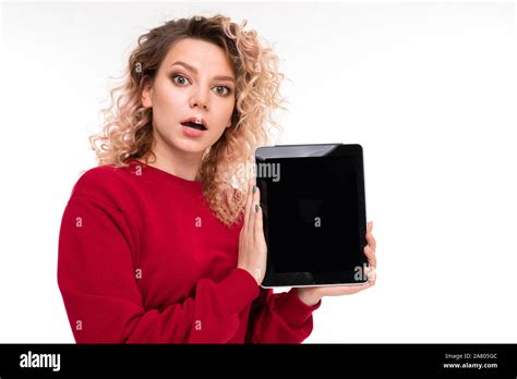 Caucasian Girl With Curly Fair Hair Holds A Tablet And Is Surprised