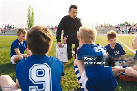 코치는 보드를 사용하여 게임 전략을 설명합니다 축구장에서 아이들을 가르치는 젊은 코치 축구 코치가 아이들을 코칭합니다 어린이를