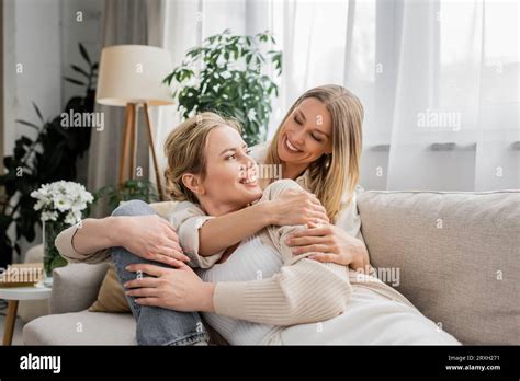 Two Lovely Beautiful Sisters Hugging Warmly On Sofa Looking At Each Other Togetherness Bonding