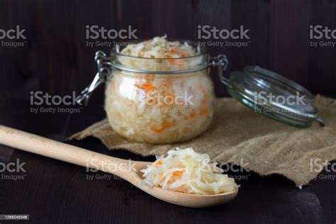 검은 색 배경에 유리 항아리에 허브와 당근과 수제 소금에 절인 양배추 나무 테이블에 자루와 숟가락에 절인 양배추 복사 공간을
