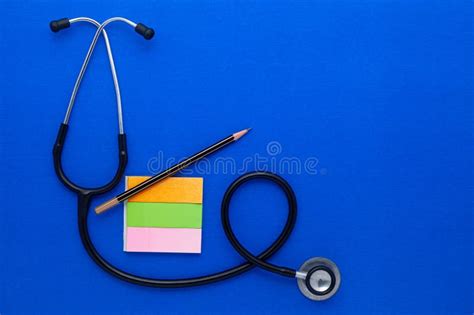 Medical Stethoscope With A Pencil And Sticky Notes Isolated On Blue