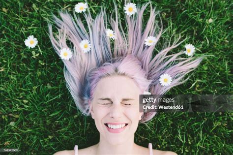 Portrait Of Woman Lying On Grass With Eyes Closed And Daisies On Hair