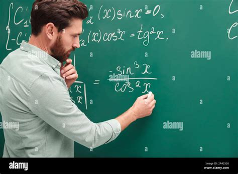 Mature Teacher Explaining Mathematics At Chalkboard In Classroom Stock