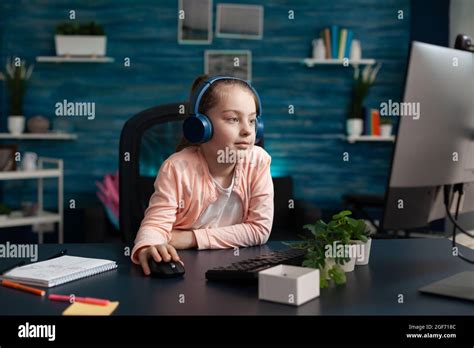 Clever Babe Girl Using Computer Monitor At Home While Wearing Headphone Set Listening To