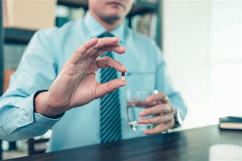물 한 잔으로 일하는 사업가는 손에 약을 걸립니다 작업 및 아픈 개념 남자에 대한 스톡 사진 및 기타 이미지 남자 알약