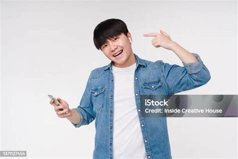 춤추는 활성 아시아 의 젊은 남자 소년 학생 은 이어버드를 보여주는 휴대 전화에 음악을 듣고 사운드 트랙 재생 목록 흰색 배경에