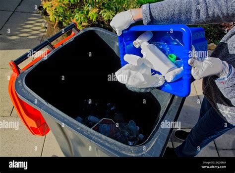 Person Tipping Empty Plastic Bottles And Metal Food Packaging In To A