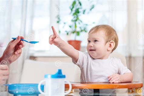 Mamá Que Alimenta La Mano De La Tenencia Del Bebé Con Una Cuchara De