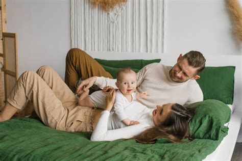 Mother And Father Are Lying On The Bed With Their Little Son At Home