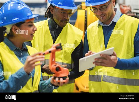 Multiracial Engineers Working Inside Robotic Factory Main Focus On African Man Safety Vest