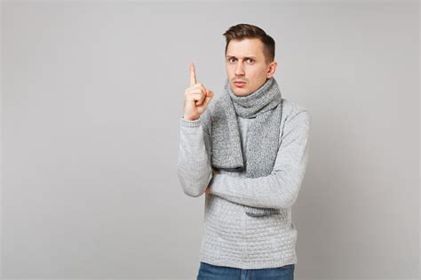 회색 스웨터에서 젊은 남자 회색 배경에 고립 된 훌륭한 새로운 아이디어를 들고 검지 손가락 스카프 건강 패션 라이프 스타일