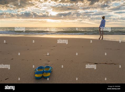 Woman Took Off Her Shoes And Went Closer To The Sea At Sunset Stock