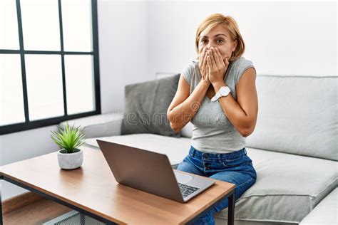 Middle Age Blonde Woman Using Laptop At Home Laughing And Embarrassed