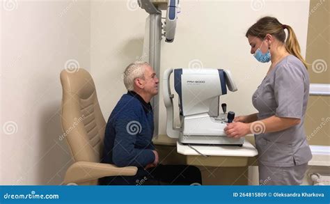 A Young Girl Ophthalmologist Conducts An Eye Test For An Elderly Man In