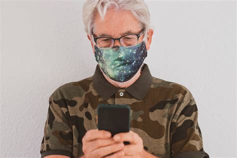 코로나 바이러스 코로나바이러스로 인해 보호얼굴 마스크를 쓰고 하얀 머리를 한 노인의 초상화는 스마트폰에 메시지 텍스트가 집중되어