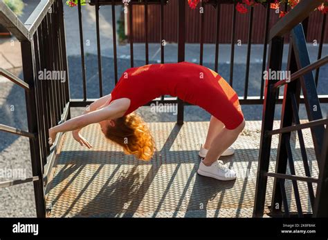Woman Wearing Red Dress Bending Over Backwards On Balcony Stock Photo Alamy