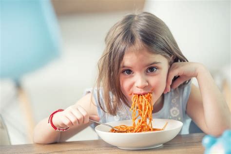 Niña Linda Niño Comiendo Espaguetis A La Boloñesa En Casa Foto Premium