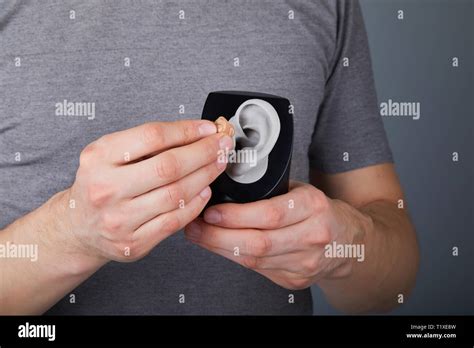 Man Showing The Use Of Hearing Aid Closeup Hearing Aids On Grey