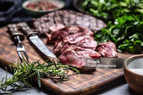 육즙이 많은 구운 쇠고기 스테이크 조각과 포크와 칼을 정육점 접시에 얹어 놓습니다 고기에 대한 스톡 사진 및 기타 이미지