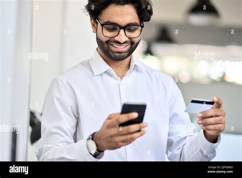 Happy Indian Business Man Holding Phone And Credit Card Using Mobile