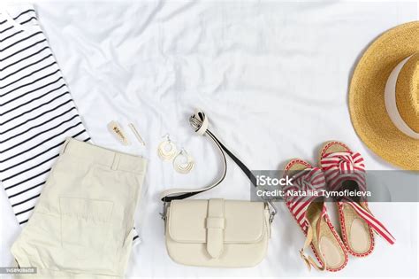 흰색 티셔츠 반바지 밀짚 모자 샌들 흰색 배경에 가방 여성의 봄 캐주얼 의상의 상위 뷰입니다 심플한 베이직 여름 여성 의류 플랫