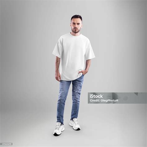 청바지를 입고 수염을 기른 남자에 흰색 오버사이즈 티셔츠의 모형 주머니에 손 전체 길이 정면 보기 스튜디오 배경에 고립되어
