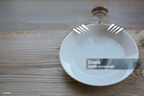 깨끗한 흰색 접시가 하나의 숟가락과 두 개의 금속 포크가있는 나무 테이블에 서 있습니다 먹을 준비가 된 것 0명에 대한 스톡