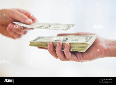 Hand Putting Dollar Bill On Top Of Stack Of Money Stock Photo Alamy